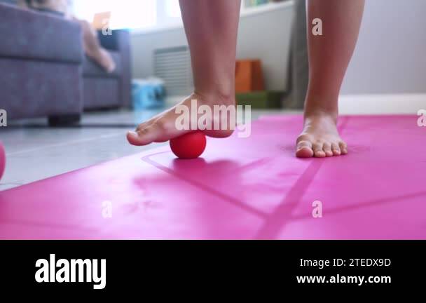 Woman massages the foot with a ball. The ball will apply pressure to ...