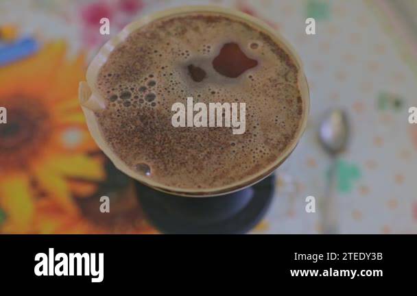 Steaming coffe bed in a dripper filled with hot water brewing coffe ...