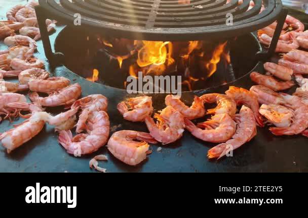 Close up footage of process of grilling fresh king prawns on brazier ...