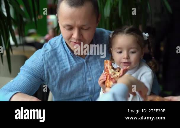 Close-up, dad and little daughter are eating Italian pizza in a cafe ...