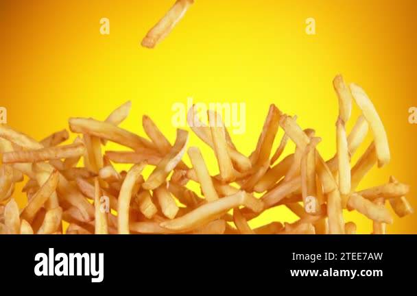 Super slow motion of flying french fries on golden background. Filmed ...