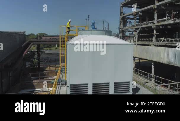 An engineer at a modern cooling tower. Worker inspecting the cooling ...
