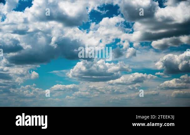 White fluffy clouds slowly float through the blue daytime sky timelapse ...