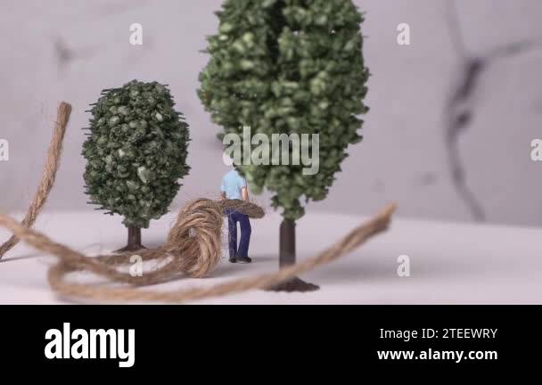 A miniature man tied to a miniature tree and rope. Concept about ...