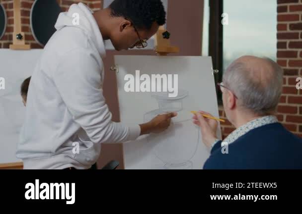 Young artist explaining drawing technique to elder person Stock Video ...