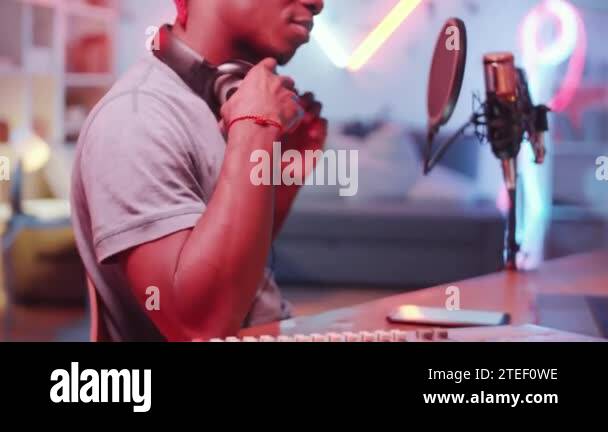 Tilt up shot of young black hip-hop producer looking at camera, putting ...