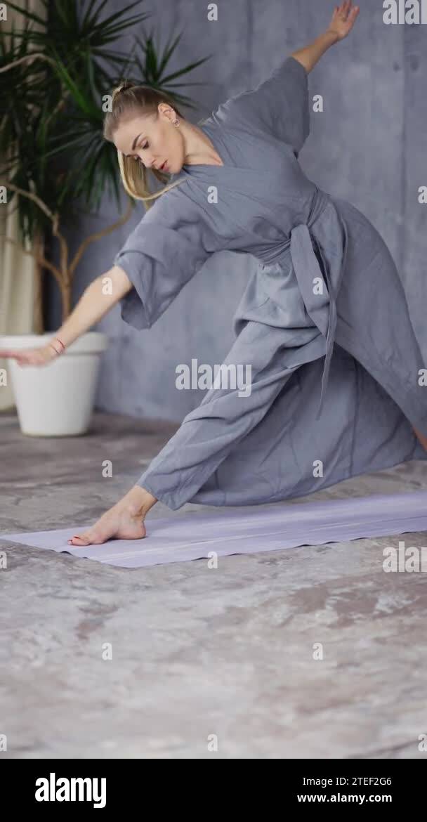 Attractive female yoga coach in robe doing Triangle Pose Utthita ...