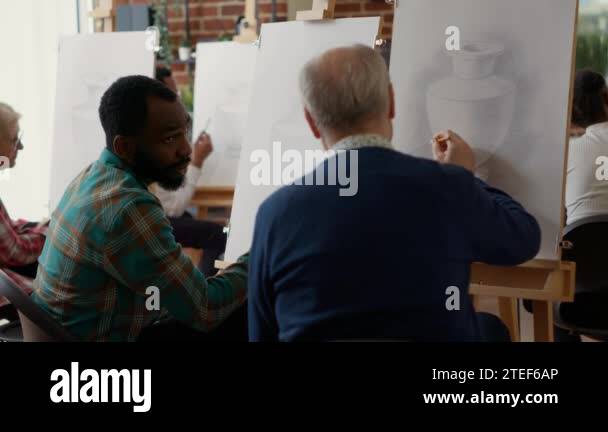 Team of art class students using pencil to draw vase design on canvas ...