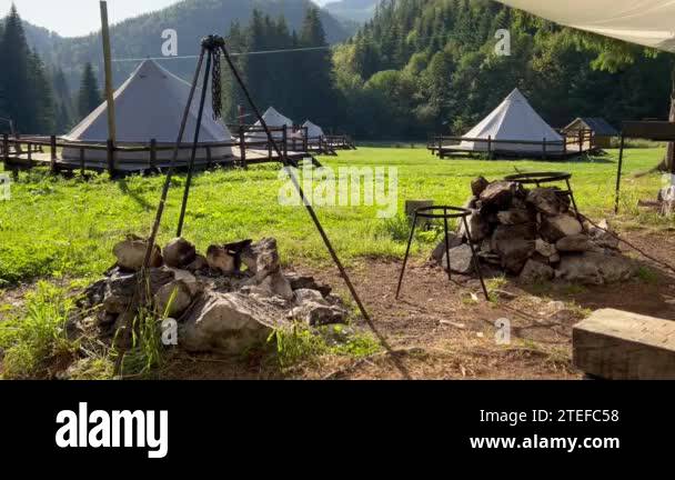 cooking area with fireplace and wooden logs in glamping tent camp site ...
