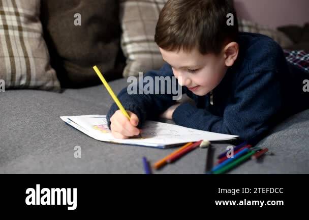 Little boy having fun on sofa, boy was coloring cartoons on coloring ...