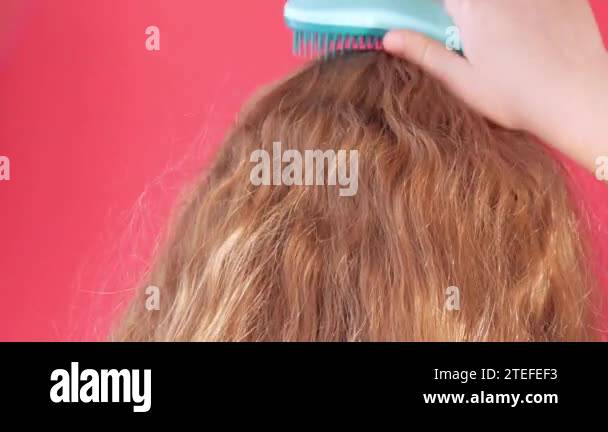 Girl combing dry tangled wavy hair with brush in hand close-up 4k pink ...