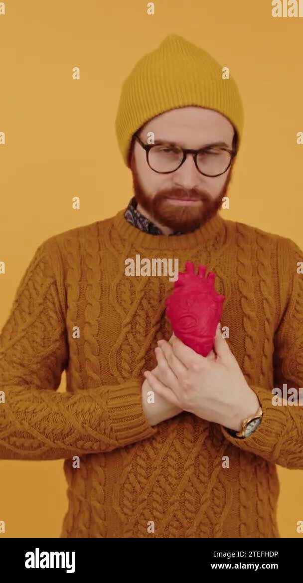 3D human heart model is beeing held by a man wearing orange sweater ...