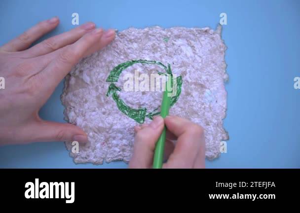 Womens hands draw a sign of reuse with a green felt-tip pen. Drawing on ...