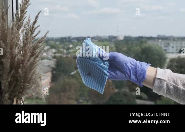 Cleaning the window. A young woman cleans and polishes windows Blue ...
