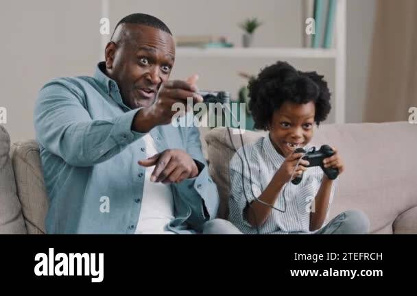 Mature african american father with little daughter playing video games ...