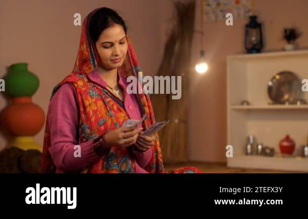 A happy female farmer of an Indian village counting her last month's ...
