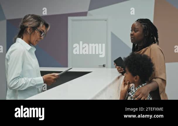 Tracking side-view of young Black mother of ten-year-old boy having ...