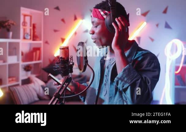 Tilt down shot of young Afro-American man in headphones looking at ...