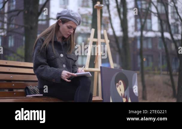 Concentrated skilled woman drawing sketch with picture at easel at ...