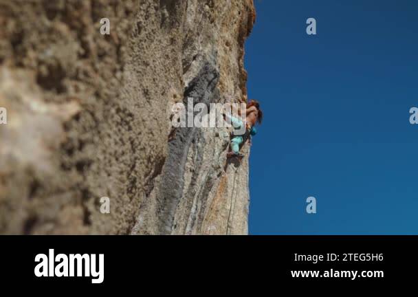 bottom view of muscular strong man rock climber climbs on vertical ...