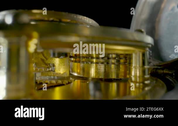 Inside view of a moving clockwork of golden mechanical clock on black ...