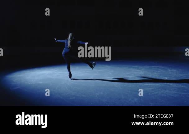 Young figure skating girl gracefully slides on the ice in the ice arena ...