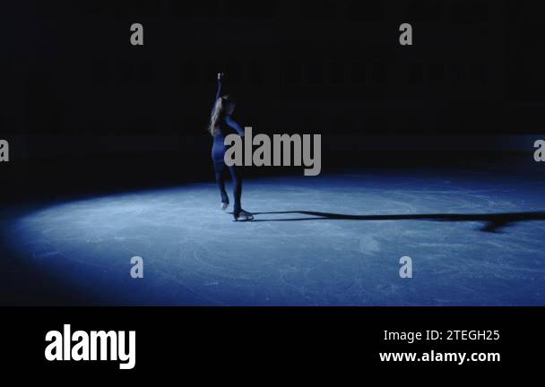 Young figure skating girl gracefully slides on the ice in the ice arena ...