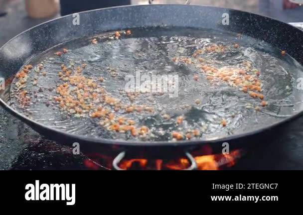 Traditional street food cooking process, large round heated cauldron on ...