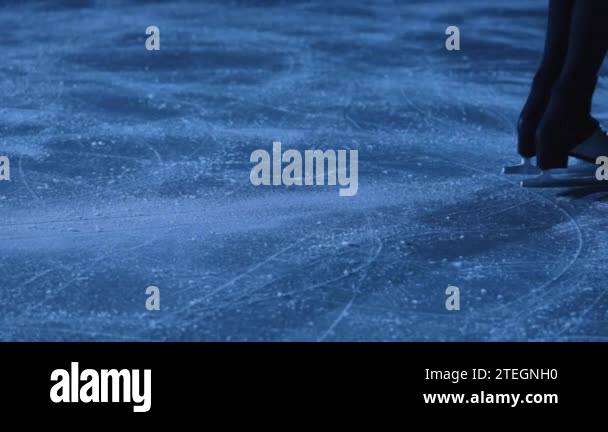 Detail shot of womens legs in figure skating skates sliding on cold ice ...