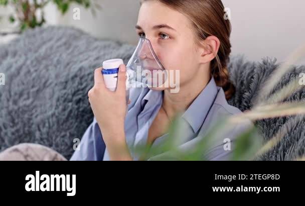 Teenage girl makes inhalation with a nebulizer equipment. Sick child ...