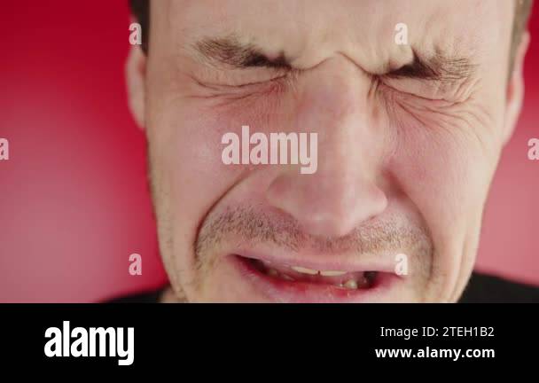 Portrait of a crying man on a red background. An unshaven man is crying ...