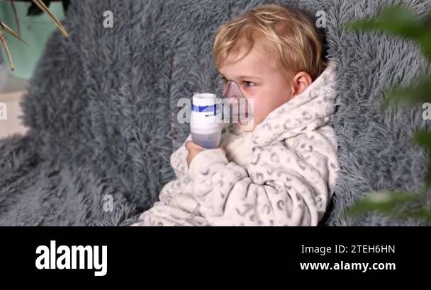 Cute baby boy makes inhalation with a nebulizer equipment. Sick child ...