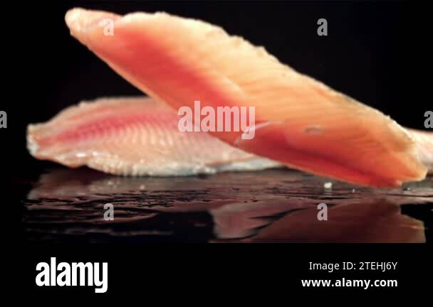 Fish fillets fall on a wet table with splashes. Filmed on a high-speed ...