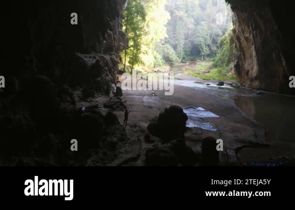 Woman explorer in dark cave, looking into distance, try to find exit ...