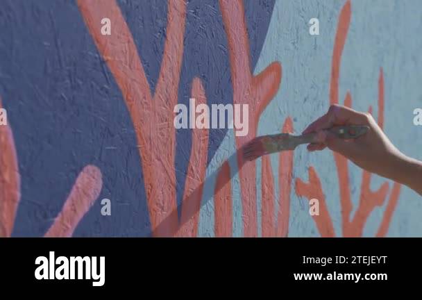 A dynamic rearward footage of hand painting a wooden wall while ...