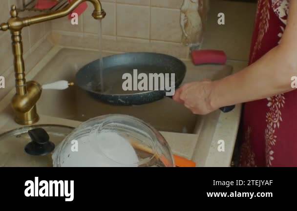Womans hand washing a dirty frying pan with a sponge with foam. Washing ...