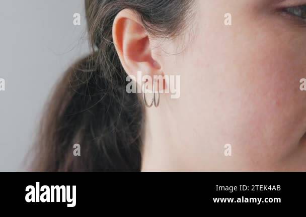Close-up of the face of a woman scratching inside her ear with an ...