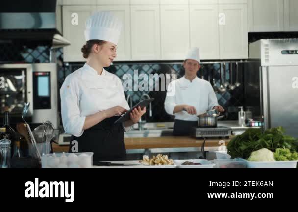 Restaurant kitchen: portrait of male and female cooks. Woman cook ...