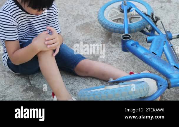 Sad little girl sitting on the ground after falling off her bike at ...
