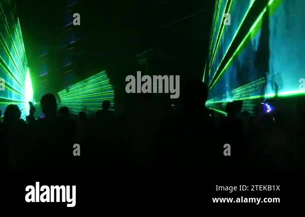 A modern laser light show, with a projection on smoke, a crowd of ...