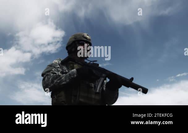 Soldier with sub-machine gun down, aiming, firing, and lowering weapon ...