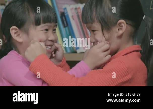 Asian sisters touch each other's cheeks and smile face to face. two ...