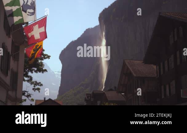Flaggs wafting in the breeze in the foreground, as the waterfall roars in the background. Swiss ...