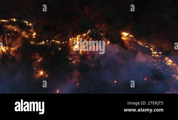 Aerial panoramic view of a forest fire at night, heavy smoke causes air ...