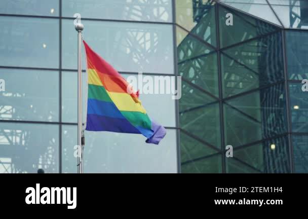 Rainbow LGBT Pride Flag Waving in Front of Modern Building Glass Facade ...