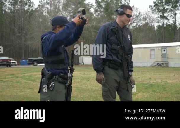 A female police officer puts on hearing protection before shooting her ...