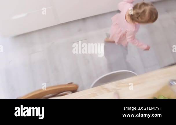 Little cute 2 years old girl having fun running around kitchen table ...
