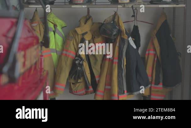 Firefighter helmets and coats hang on an equipment rack at a fire ...