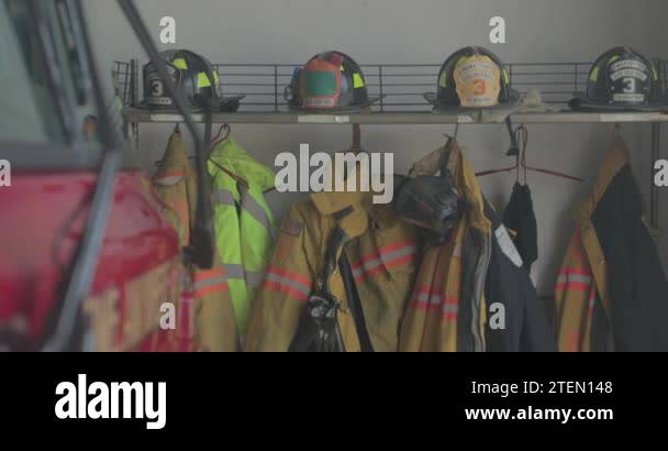 Firefighter helmets and coats hang on an equipment rack at a fire ...
