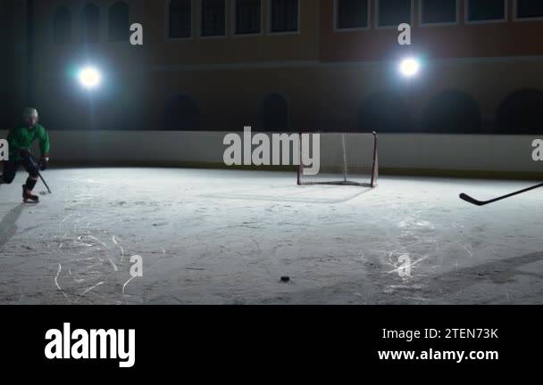 Two men in uniforms and helmets with hockey sticks skate on the ice ...